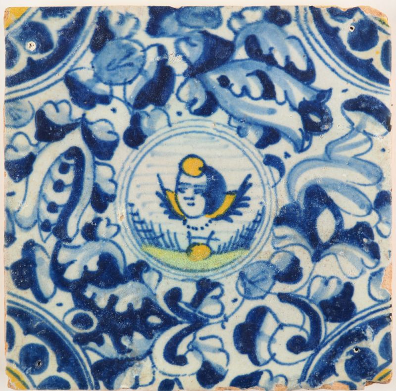 Antique polychrome Delft tile with Cherub in the center of a foglie ...